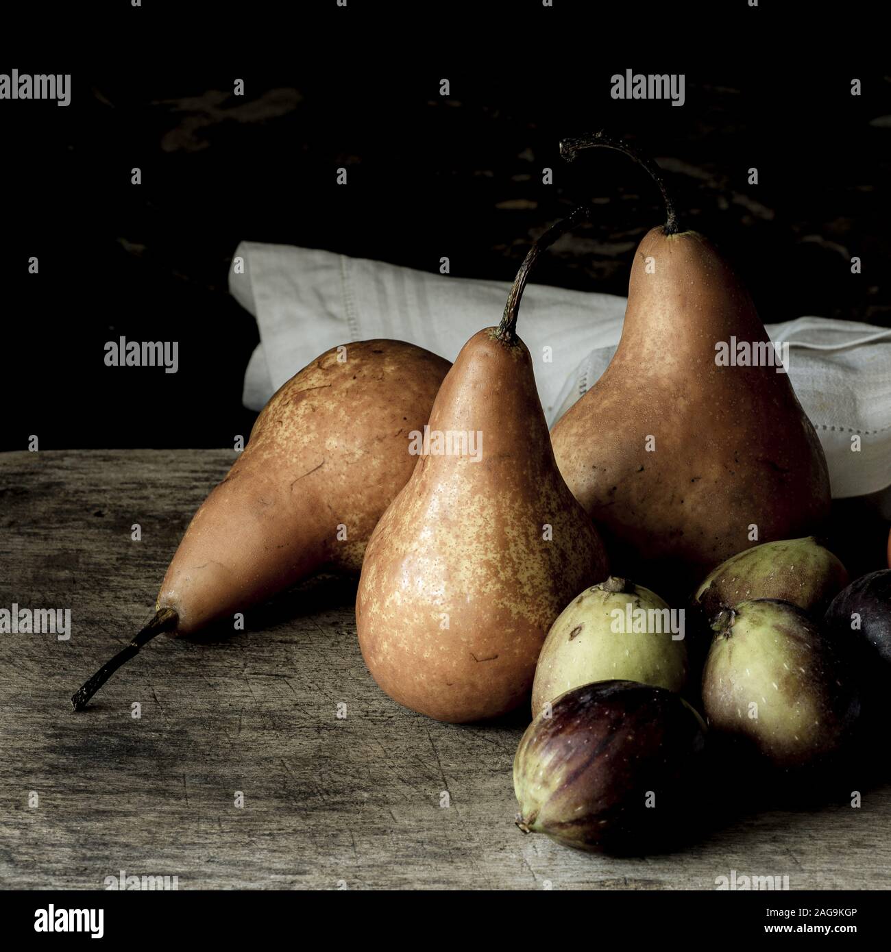 Still life photography of pears and figs on a wooden desk with a black ...