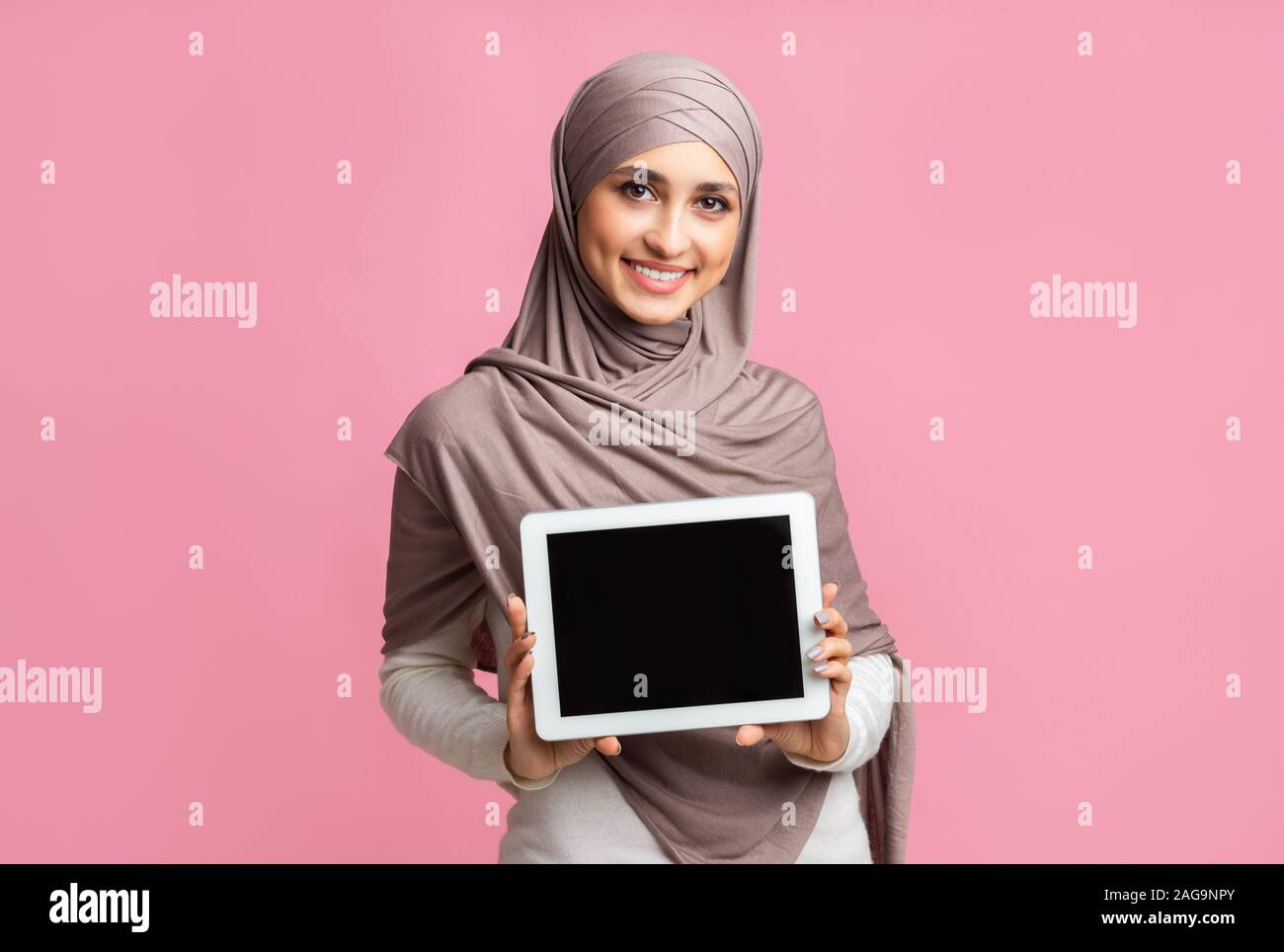 Muslim girl in hijab demonstrating digital tablet with black screen ...