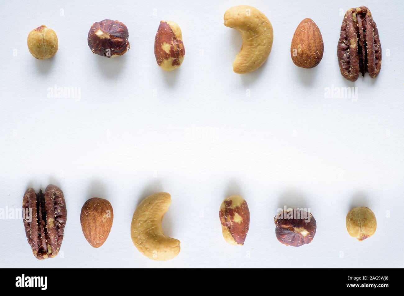 Overhead shot of different types of nuts on a white surface - great for ...