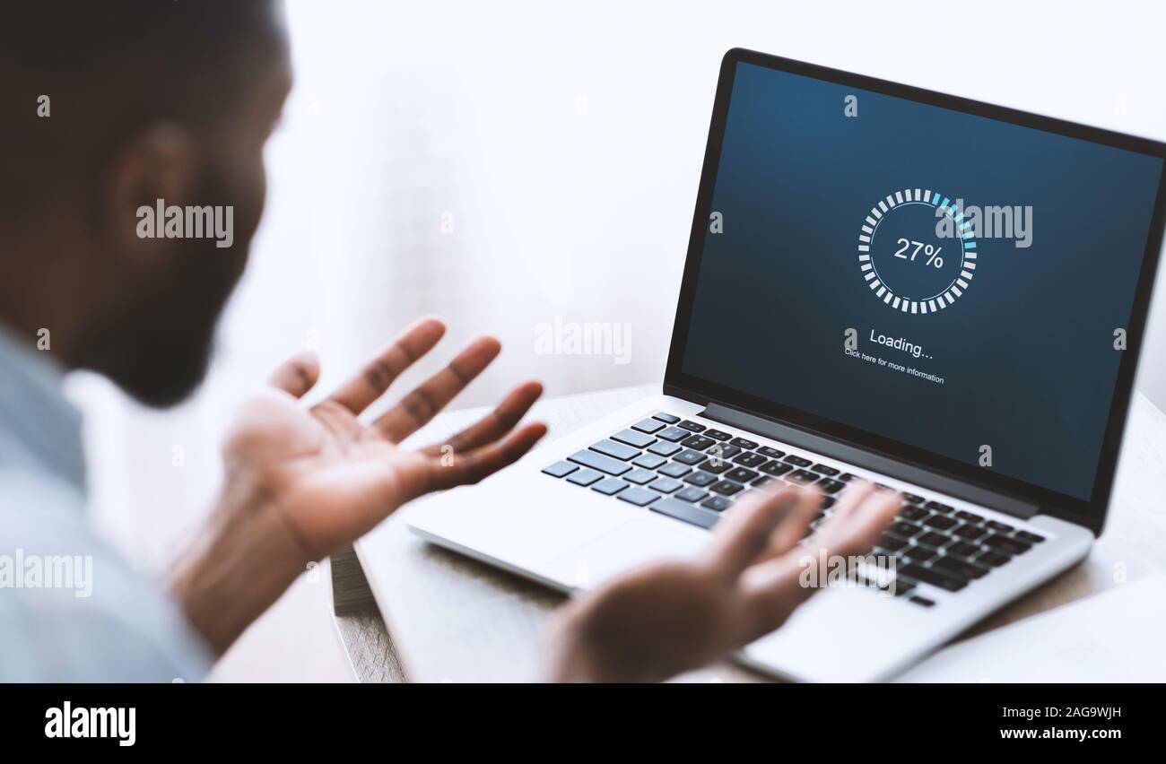 Worried african american man looking at laptop with loading screen ...