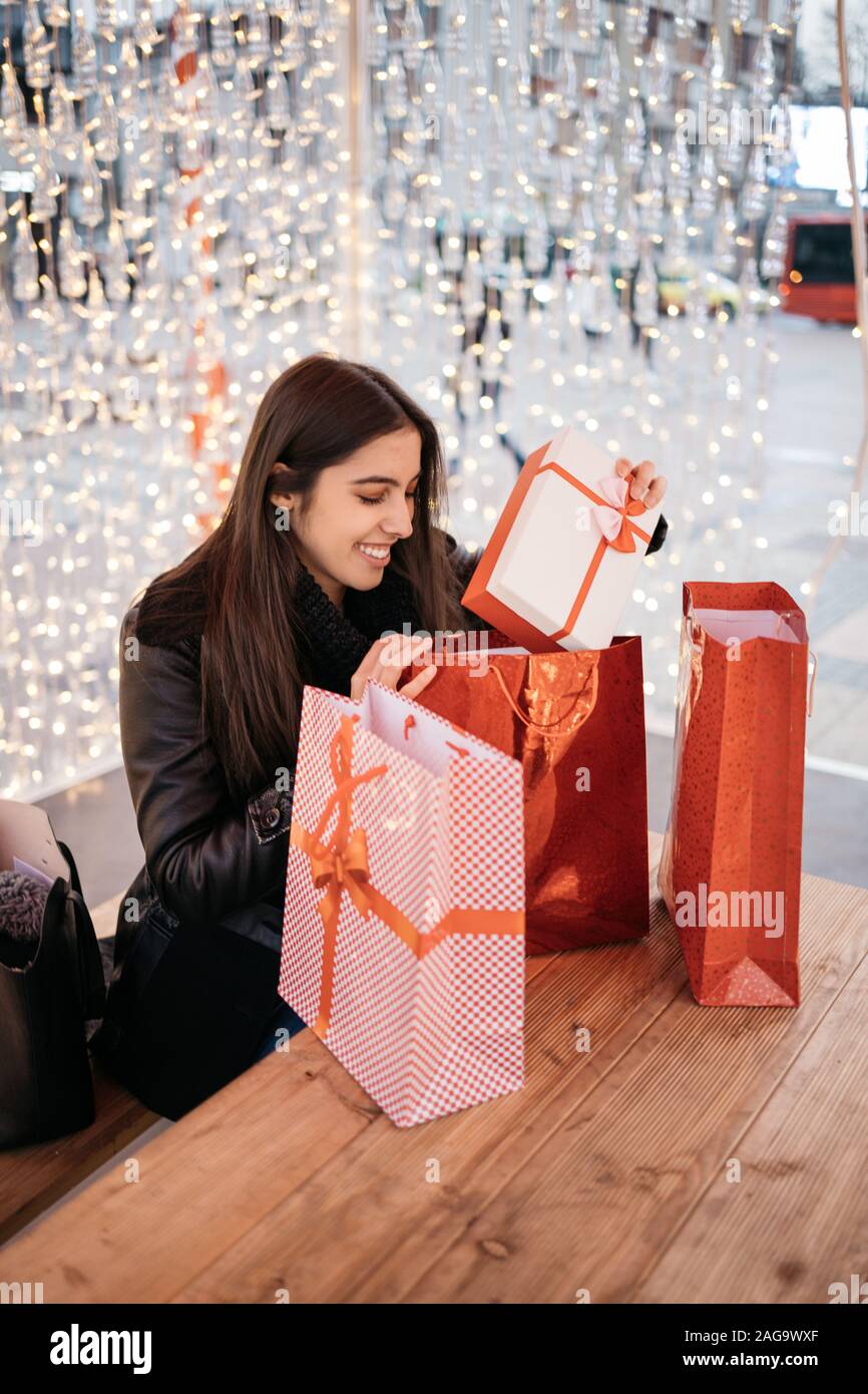 Young girl taking out wrapped Christmas present. Smiling girl pulling ...