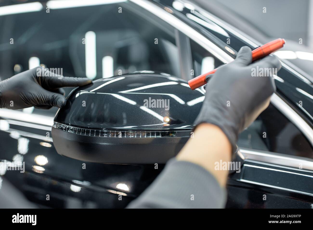 Worker examining vehicle body for scratches and damages backliting by a ...