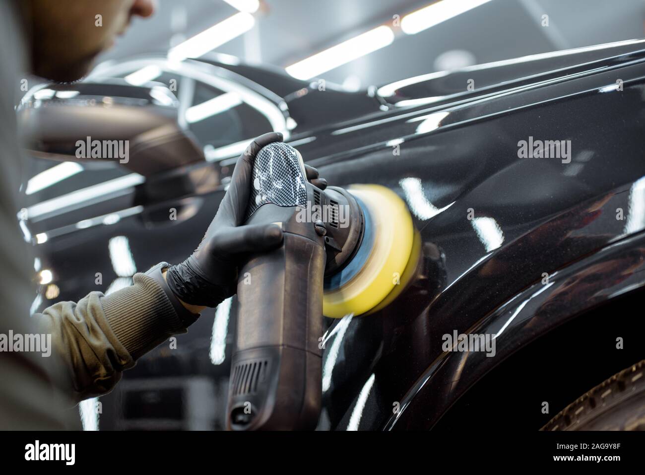 Worker polishing vehicle body with special grinder and wax from ...