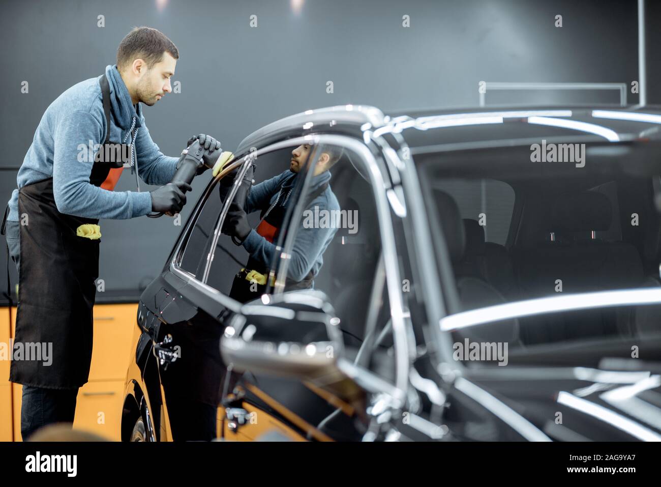 Worker polishing vehicle body with special grinder and wax from ...