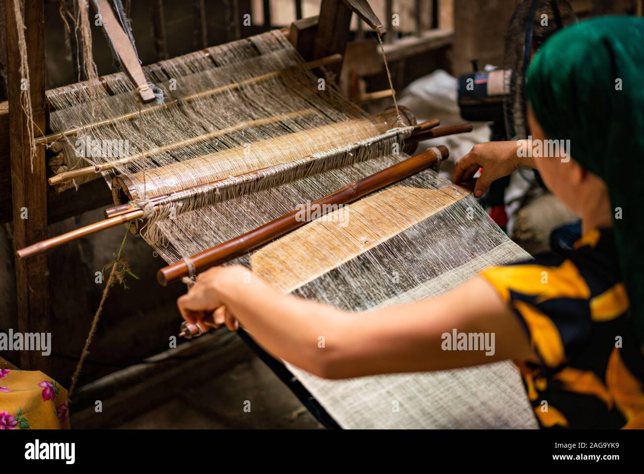High angle shot of a Vietnamese female weaving a piece of fabric in a ...