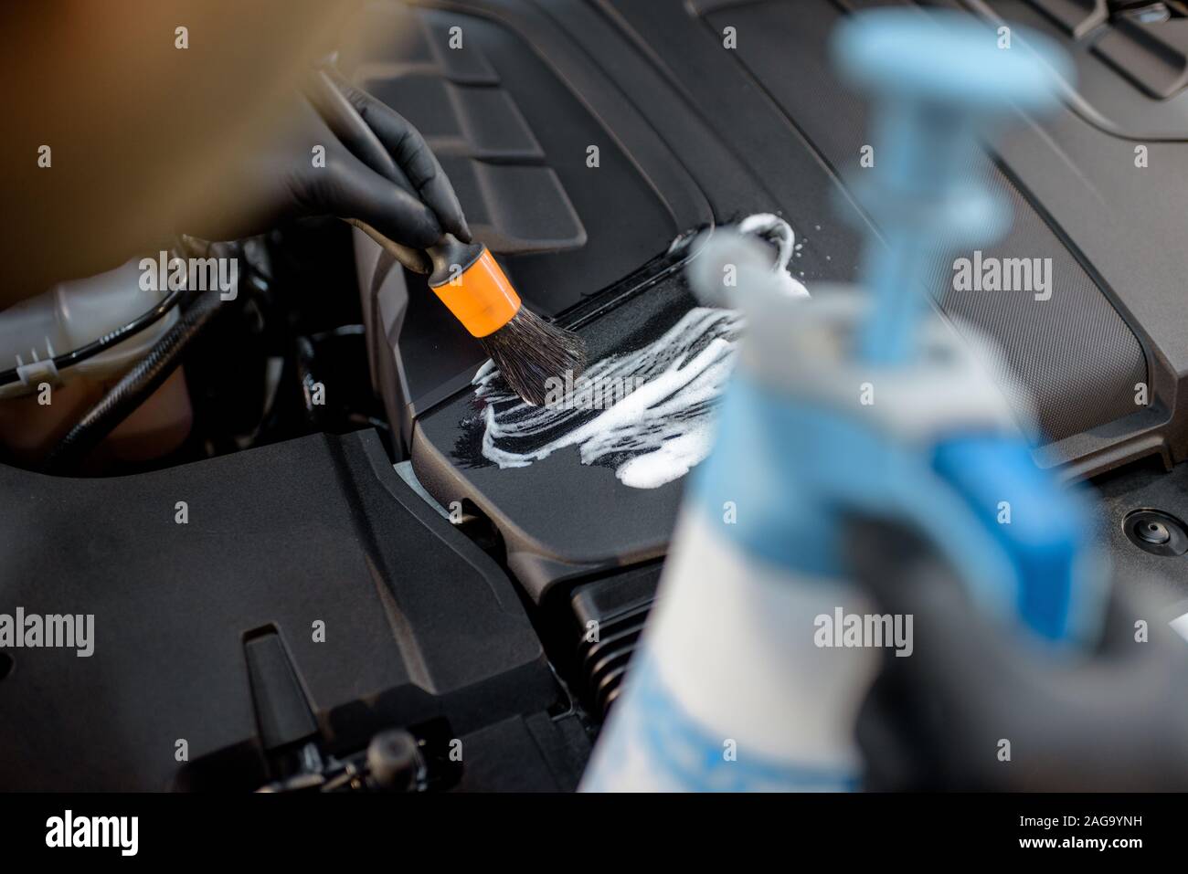 Man performs a professional car cleaning, washing engine with brush and ...