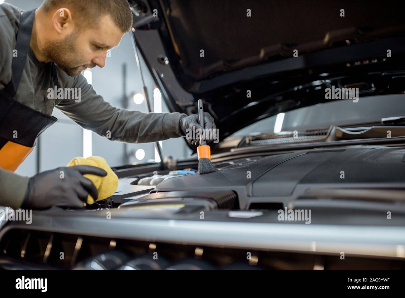 Man performs a professional car cleaning, washing engine with brush and ...