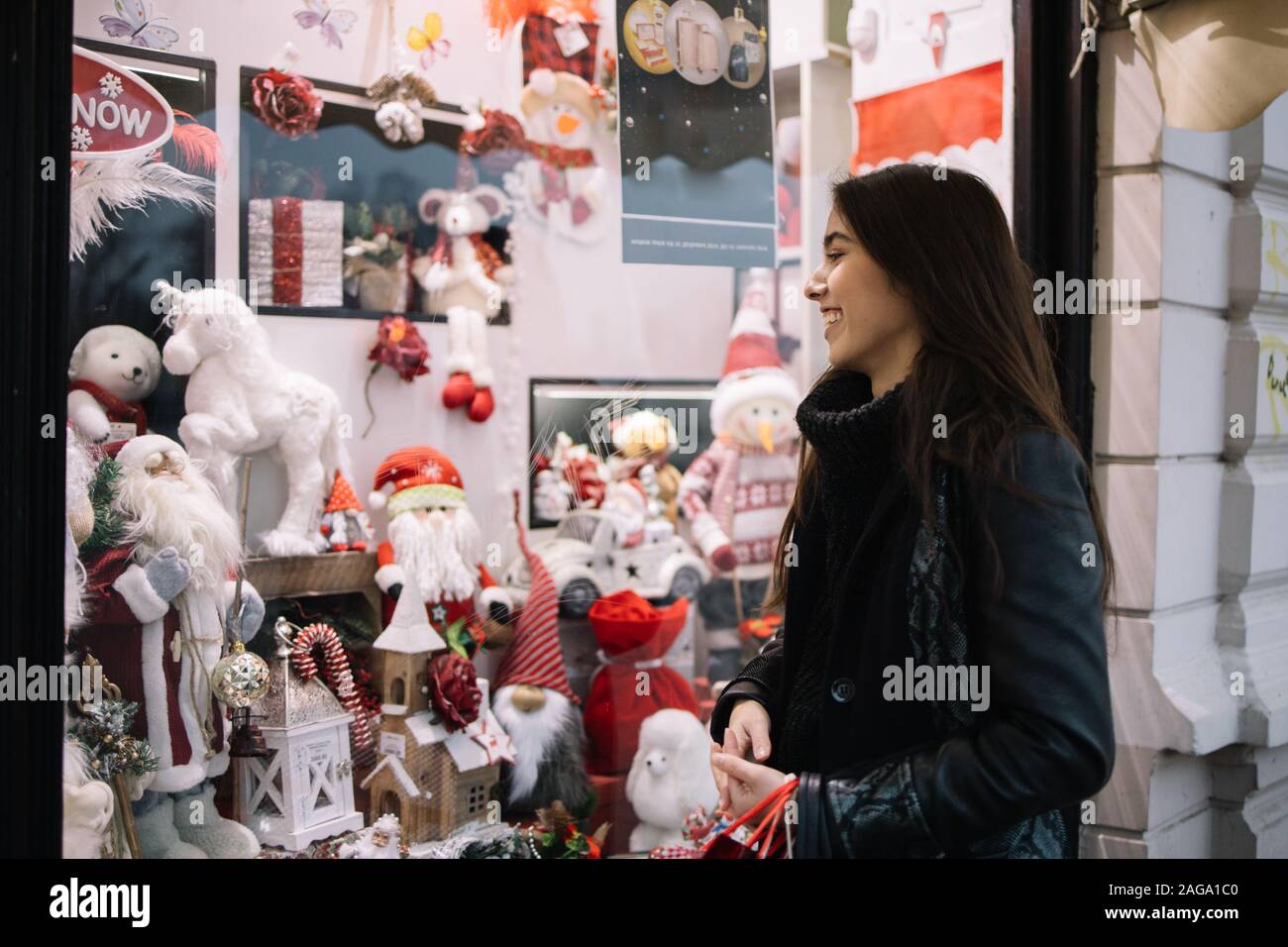 Happy girl looking into toy store window. Pretty girl standing at ...