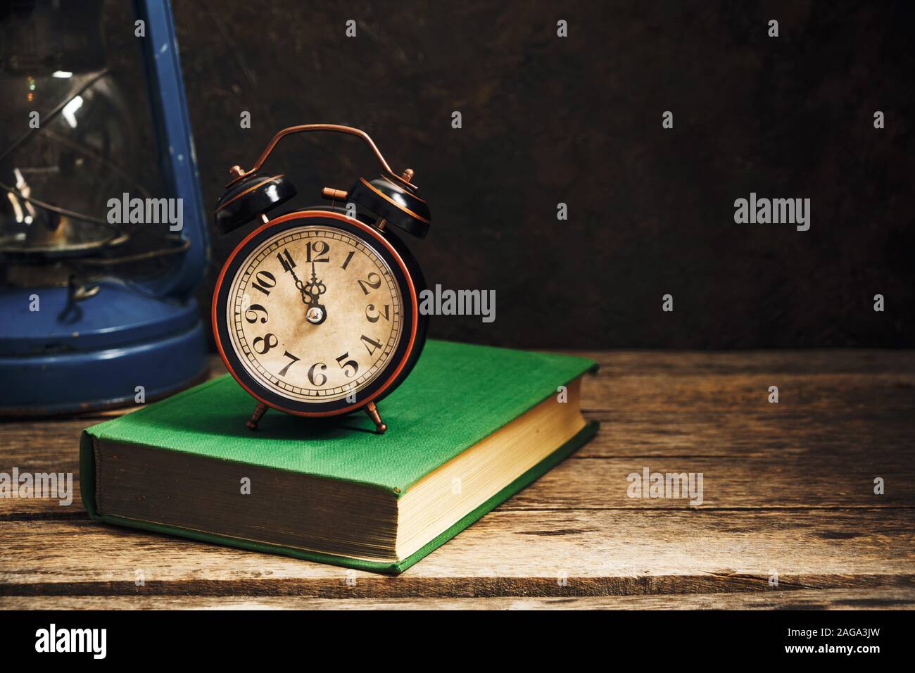 Old retro alarm clock in rustic interior with books and kerosene lamp ...