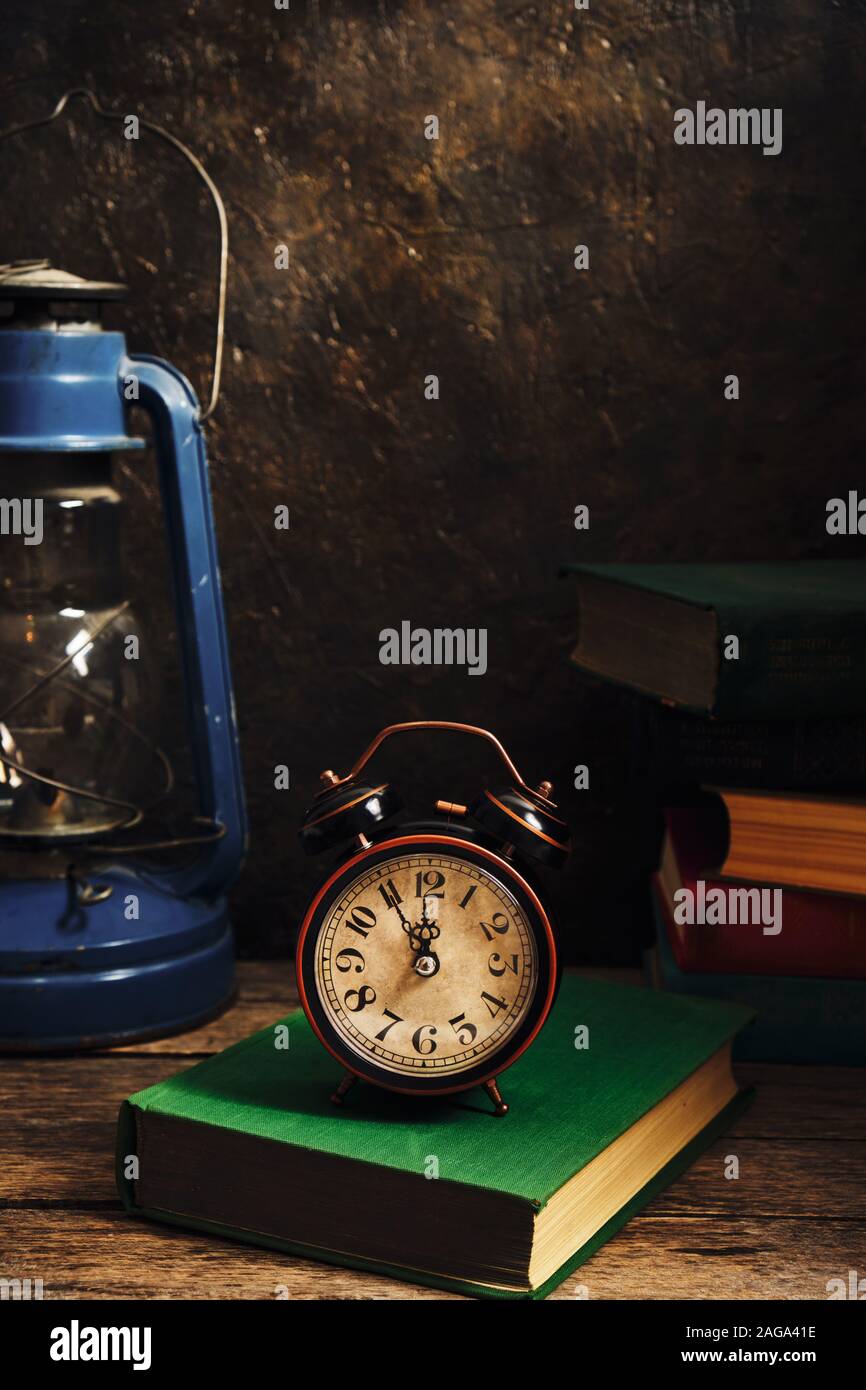 Old retro alarm clock in rustic interior with books and kerosene lamp ...