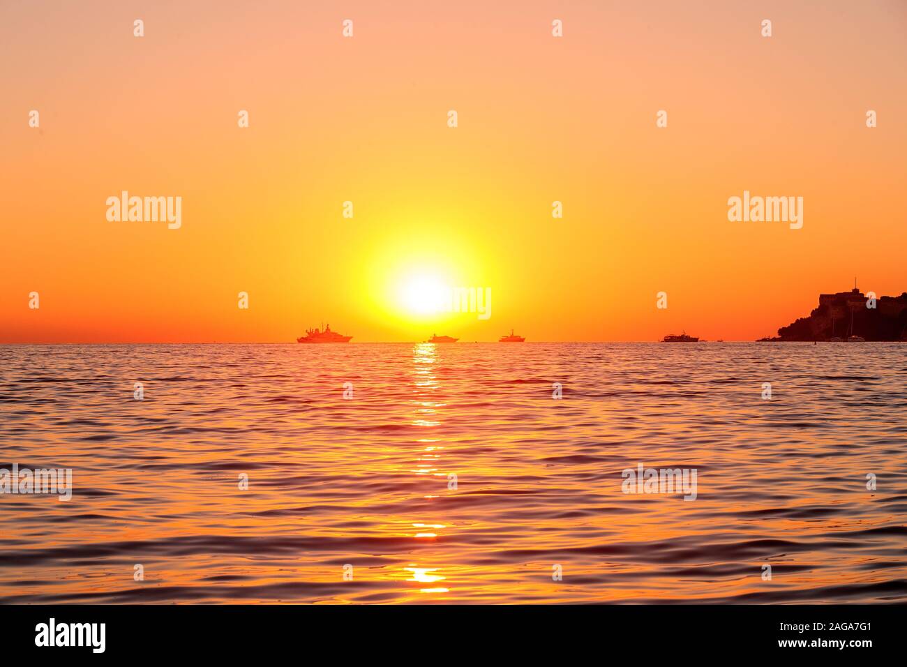 Breathtaking shot of the sunset over the sea and silhouettes of ships ...