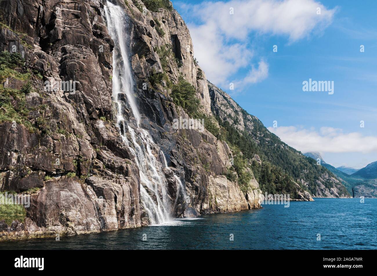 Breathtaking shot of the water falling from the rocks into the lake in ...