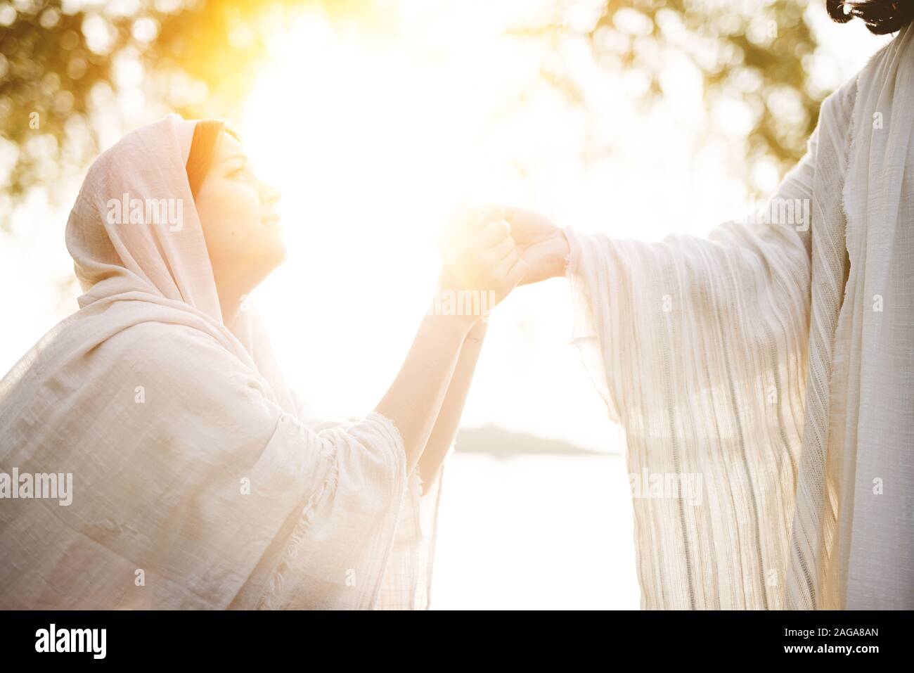 Female wearing a biblical robe and grabbing the hand of Jesus Christ ...