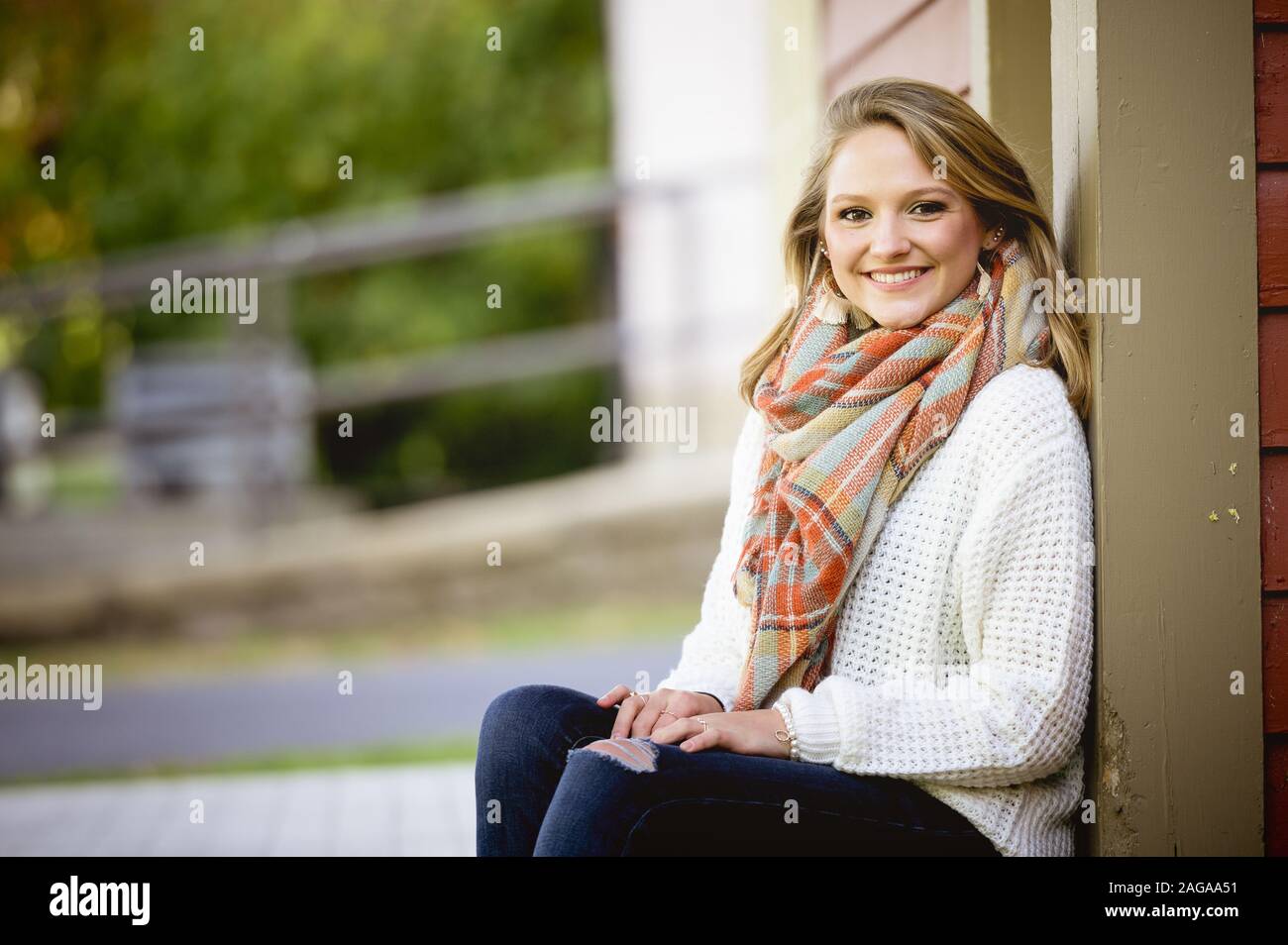 Shallow focus shot of a female leaning against a wall and smiling at ...
