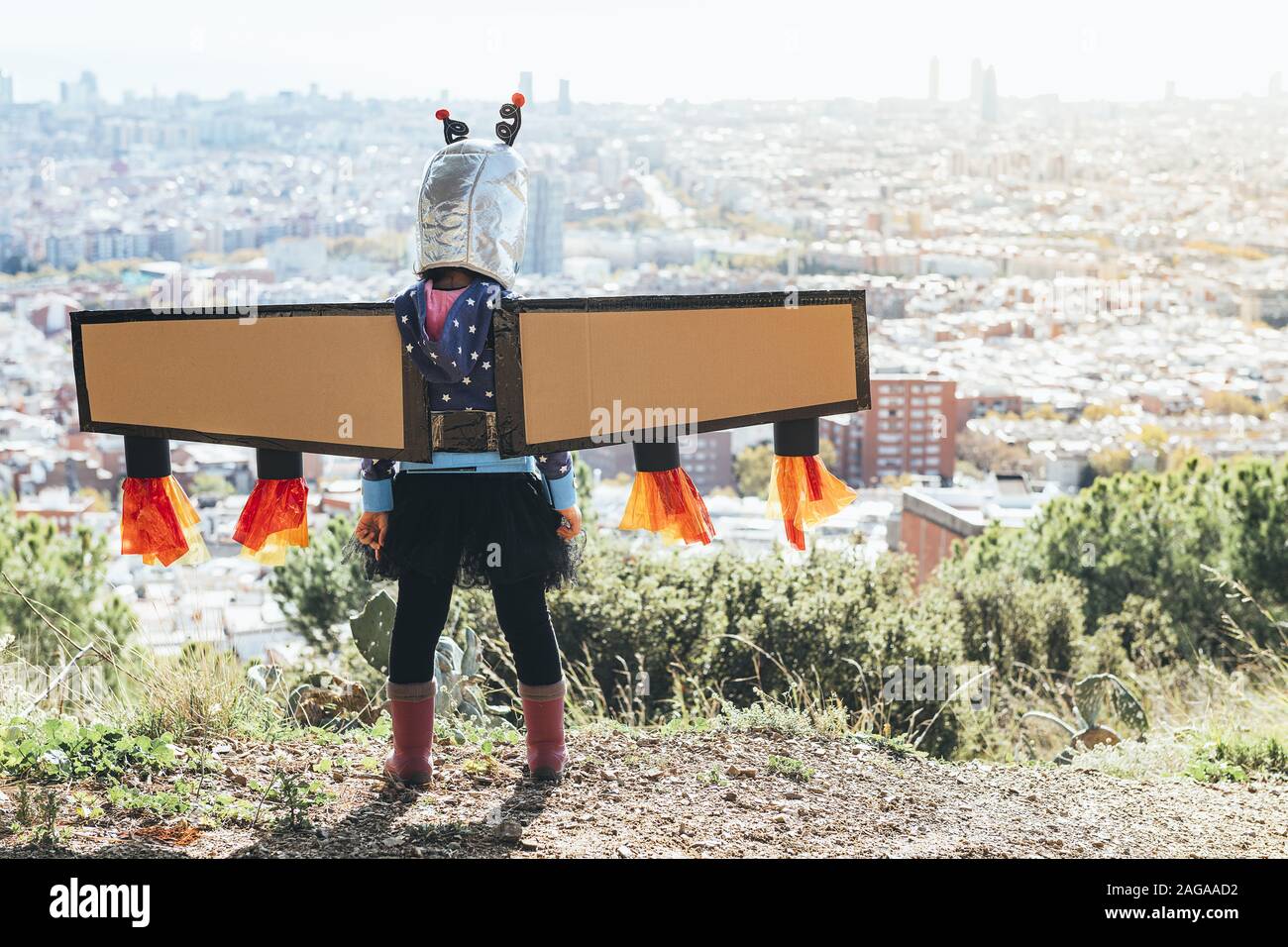 rear view of a little child girl disguised as a superhero with homemade ...
