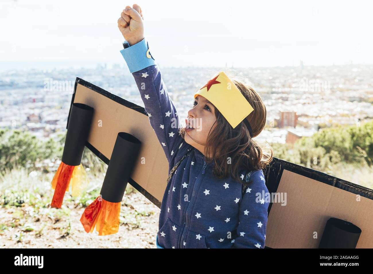 little child girl posing powerful with fist in the air disguised as a ...