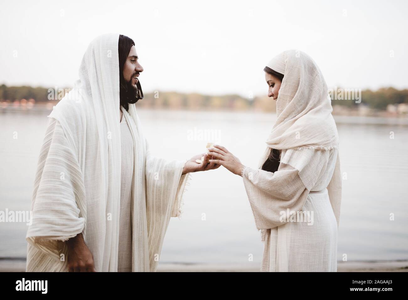 Shallow focus shot of Jesus Christ giving a piece of bread to a female ...