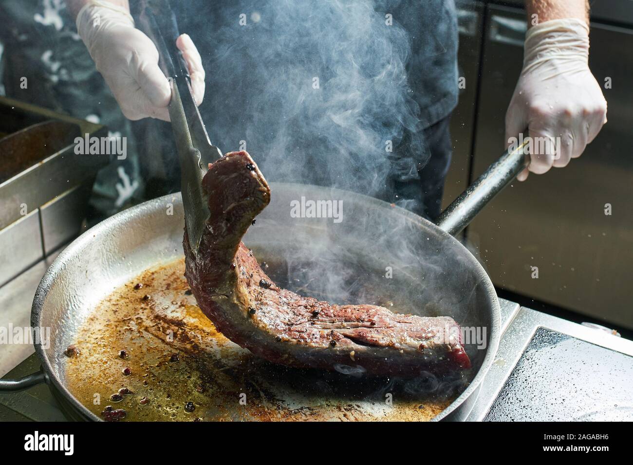 The chef works in the kitchen of the restaurant. Fresh meat roasted in ...