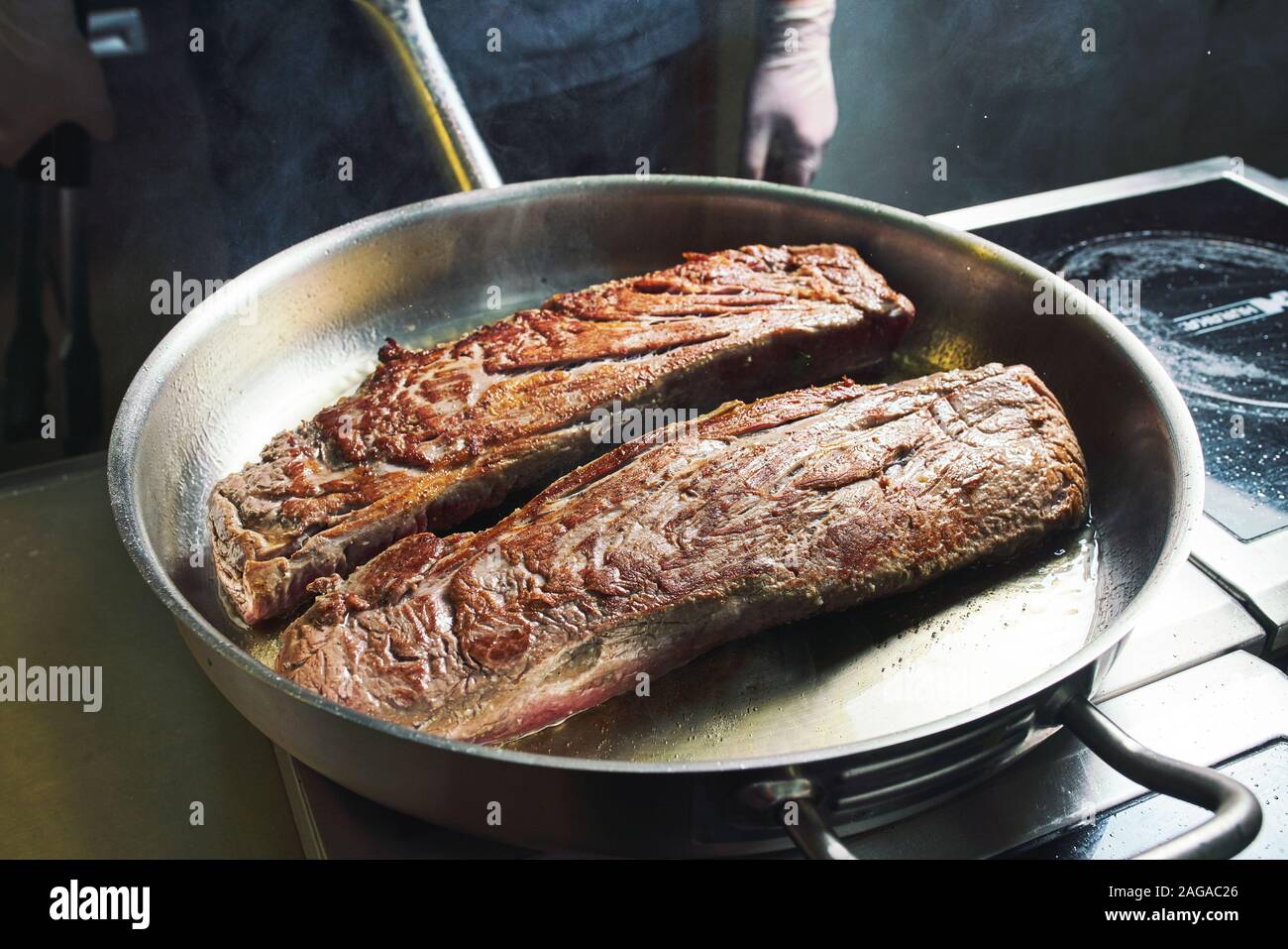 The chef works in the kitchen of the restaurant. Fresh meat roasted in ...