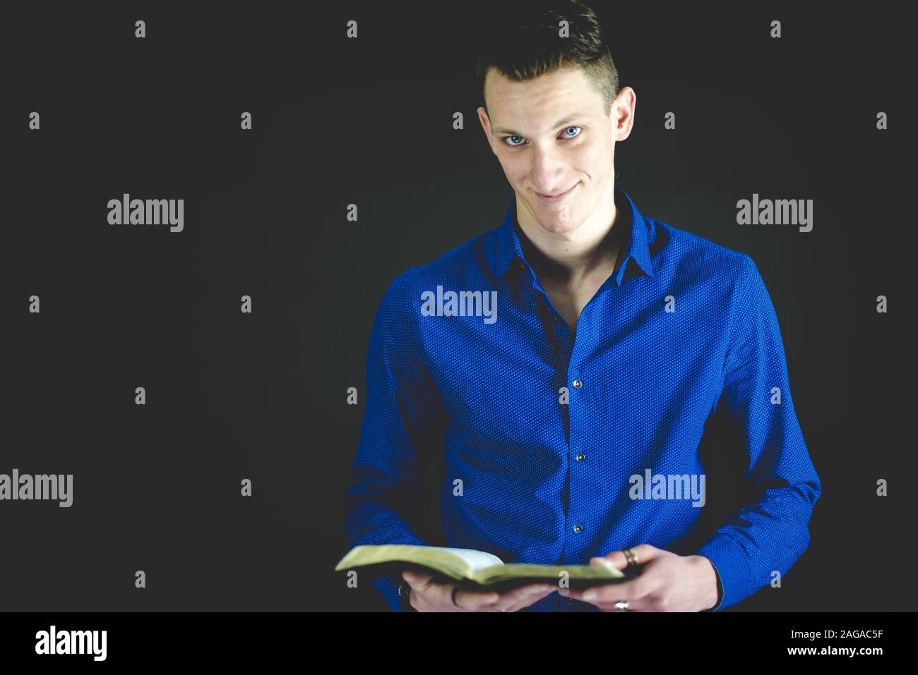 Male smiling at the camera while holding the bible with a black ...