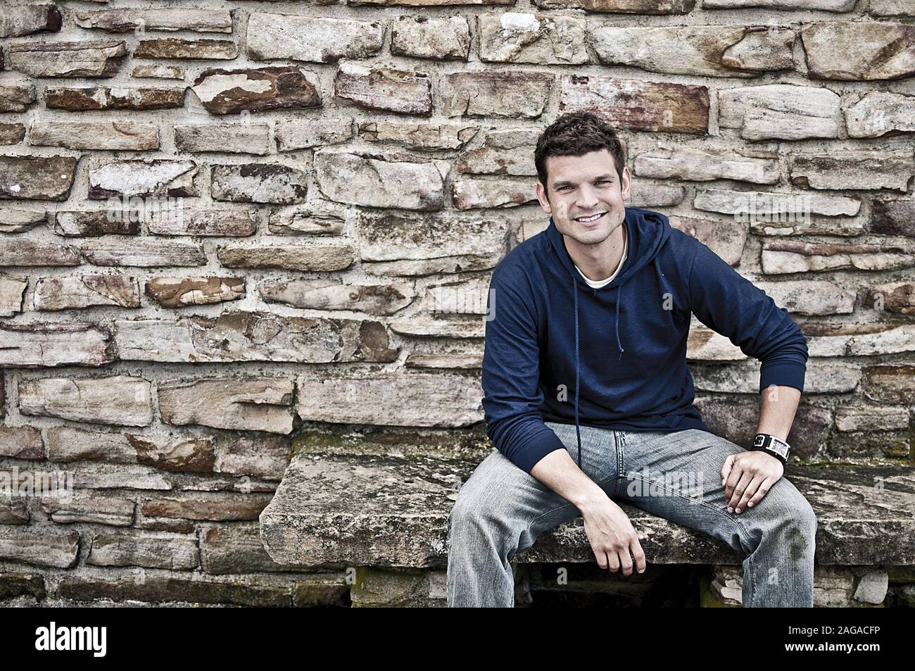 Male sitting on the bench while smiling at the camera Stock Photo - Alamy