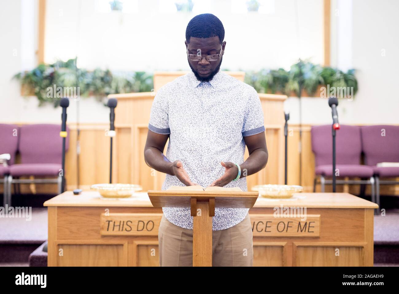 Shallow focus shot of a male reading bible near the wooden stand in the ...
