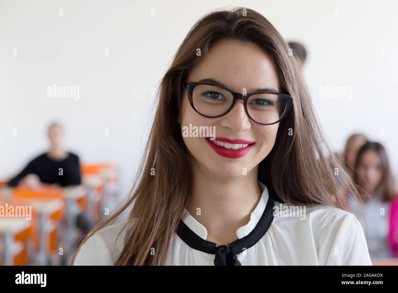Beautiful female student wearing glasses standing at university campus ...
