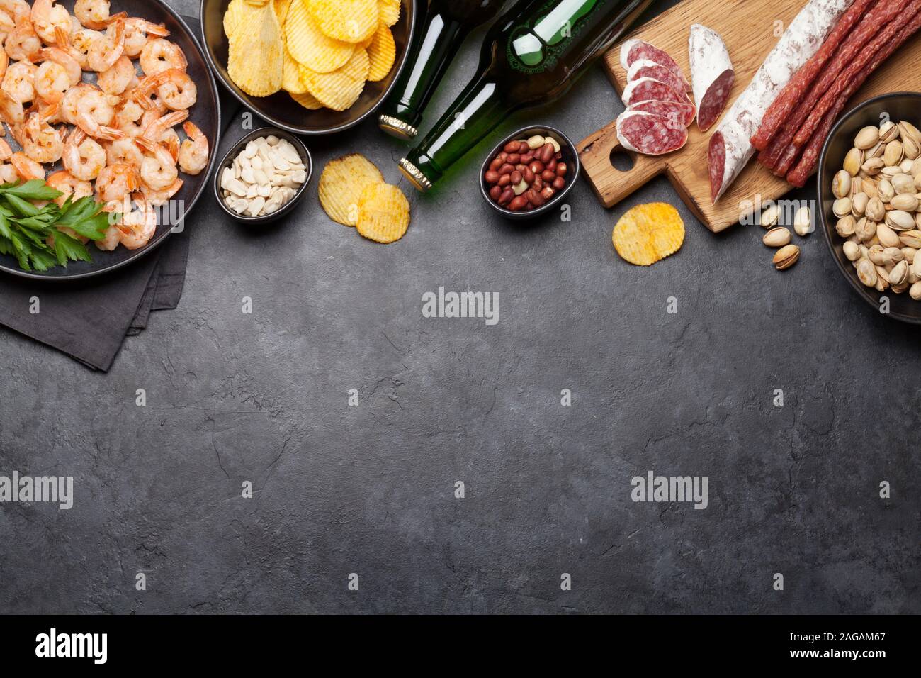 Draft beer and snacks on stone background. Nuts, chips, sausages and ...
