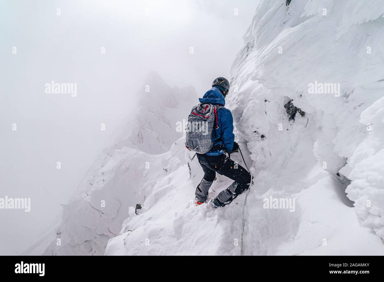 An alpinist climbing an alpine ridge in winter extreme conditions ...