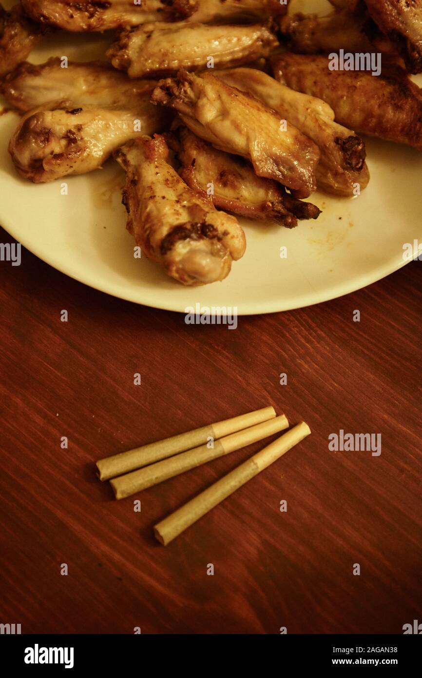 Vertical shot of marijuana blunts on a wooden table with a plate of ...