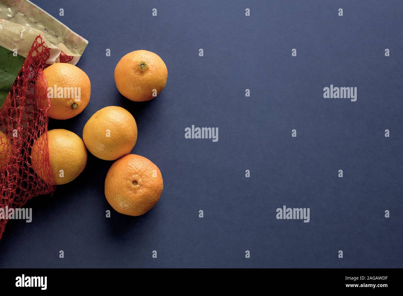 Overhead shot of oranges spilled out of the bag on a dark blue surface ...