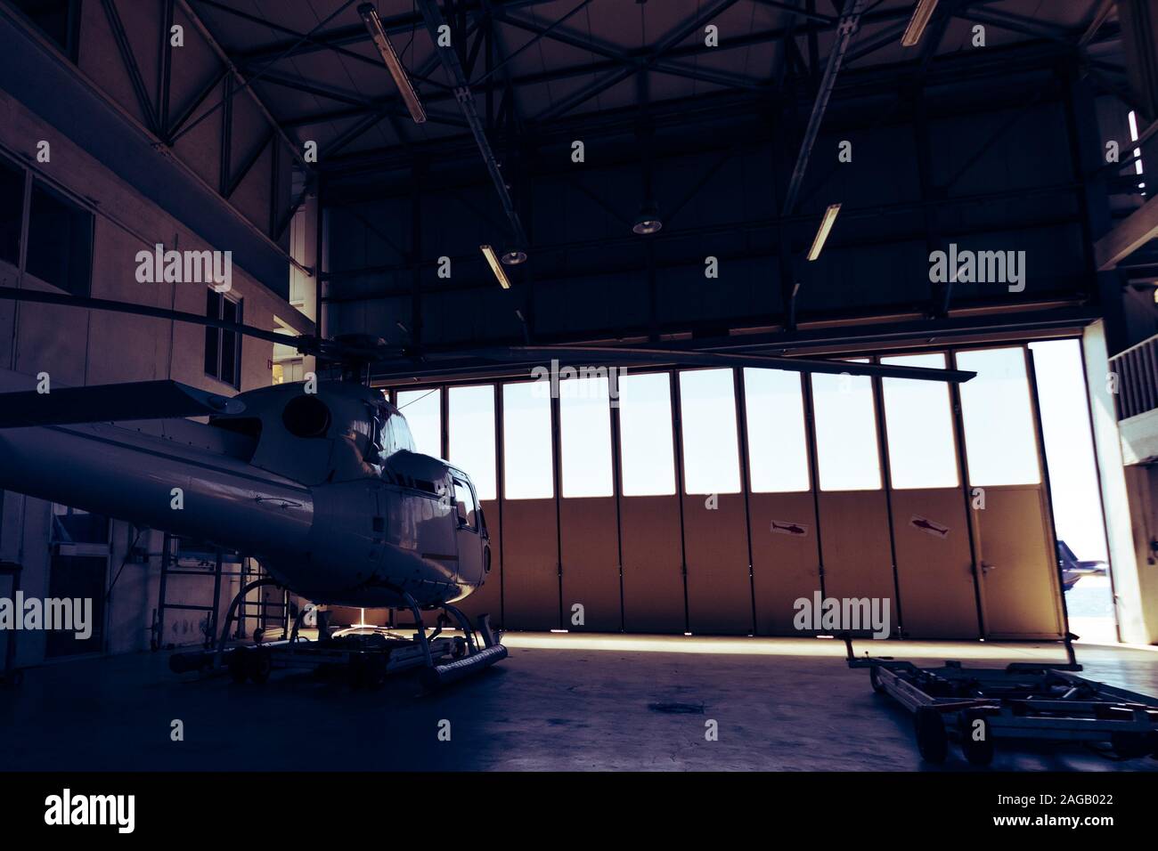 White military helicopter parked inside a garage with a closed gate ...
