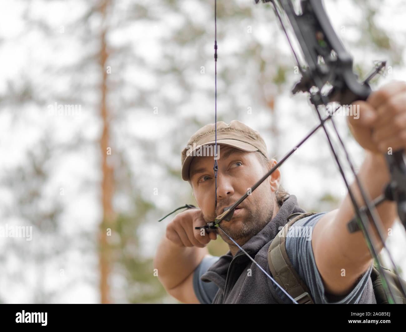 Man hunts in the forest with a bow. The hunter aims Stock Photo - Alamy