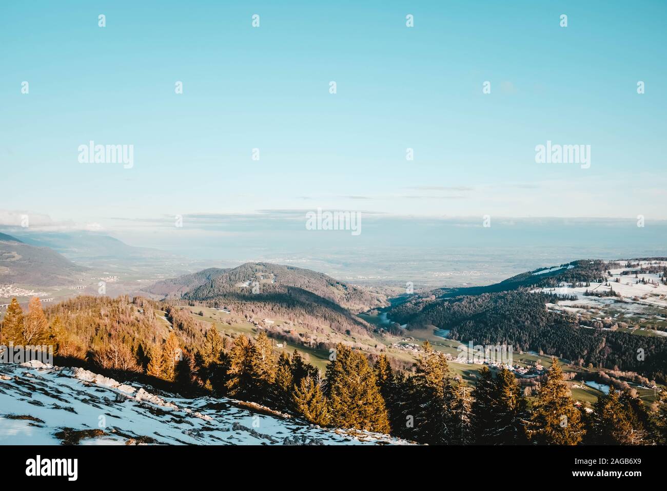 Beautiful view of the trees on a snow covered hill with the fields in ...