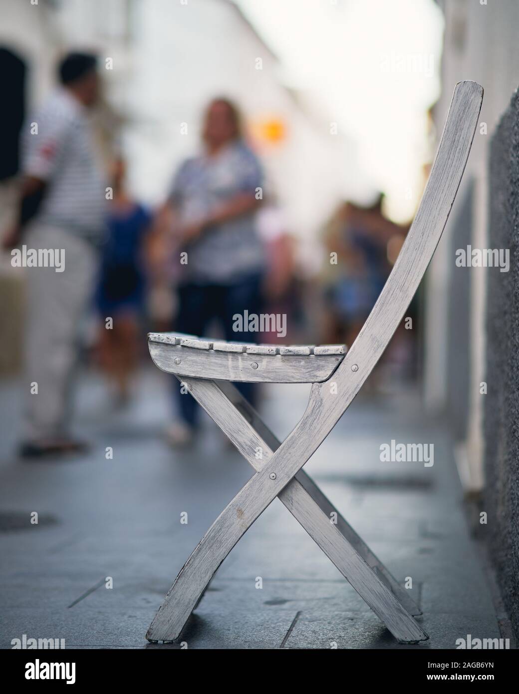 White hand painted wooden empty chair standing on a crowded street ...