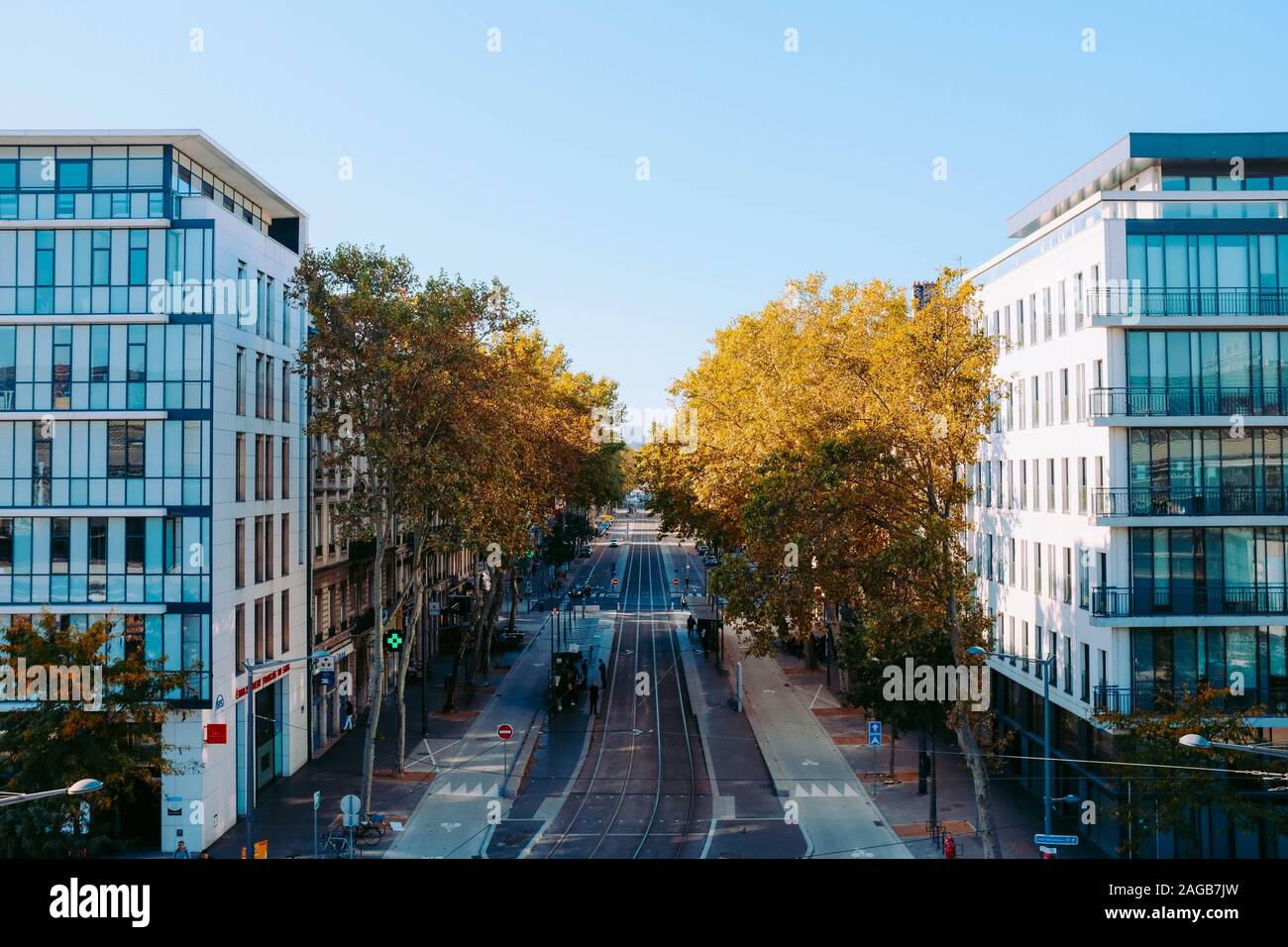 Aerial shot of an empty street surrounded by glass buildings and trees ...