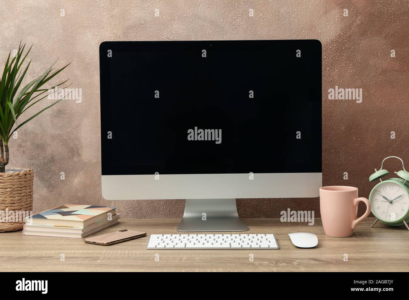 Workplace with computer and plant on wooden table. Light brown ...