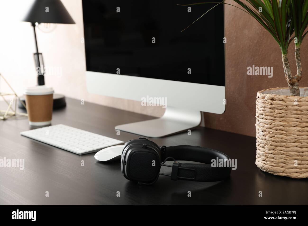 Workplace with computer and plant on wooden table. Light brown ...