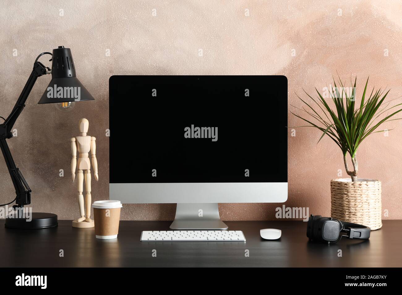 Workplace with computer and plant on wooden table. Light brown ...