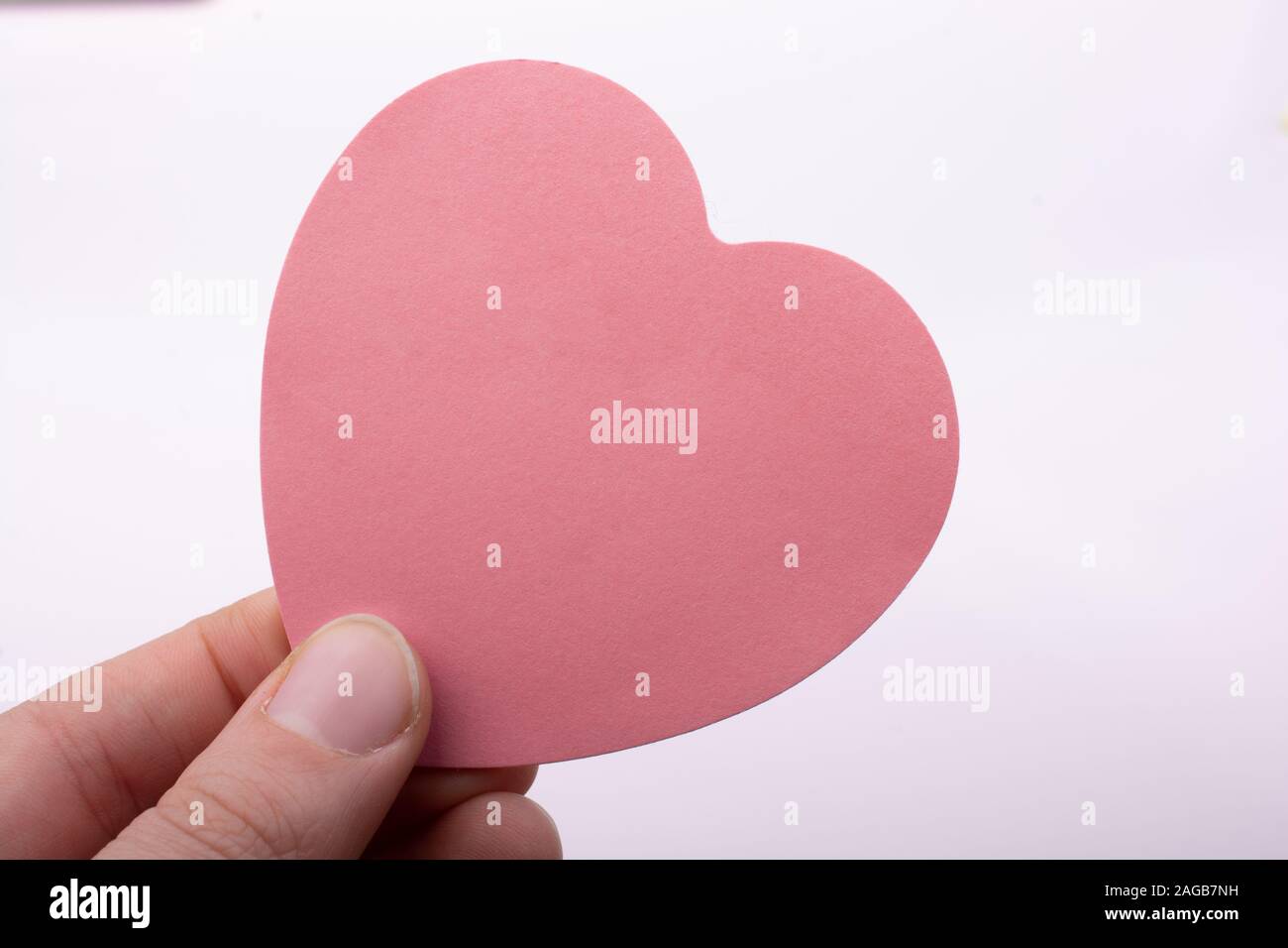 Pink color heart shaped paper in hand as love concept Stock Photo - Alamy