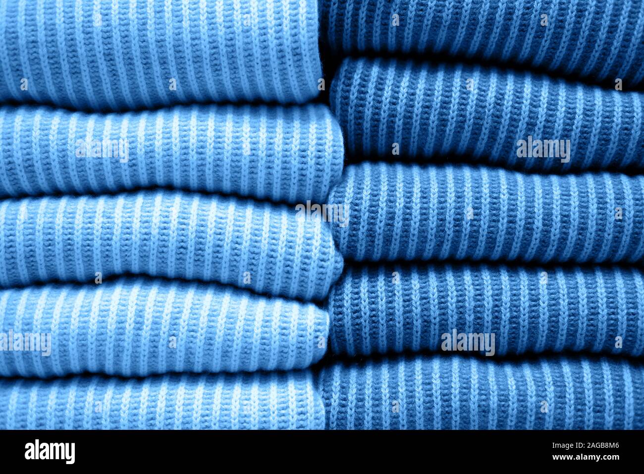 Two piles of warm red and living coral knitted sweaters in a row ...