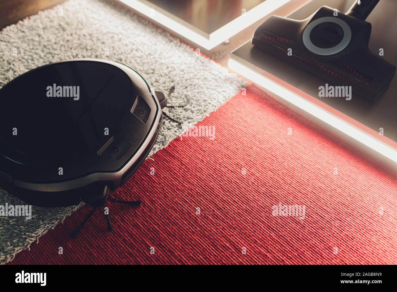 Robotic vacuum cleaner working on carpet. Traditional vacuum cleaner in ...