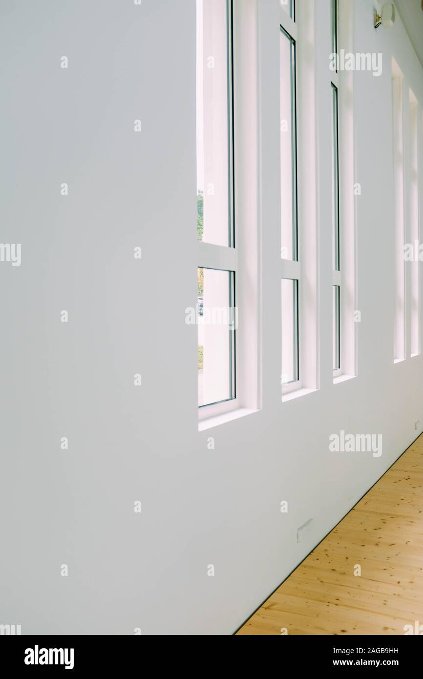Vertical shot of a white wall with glass windows in a cool house with a ...