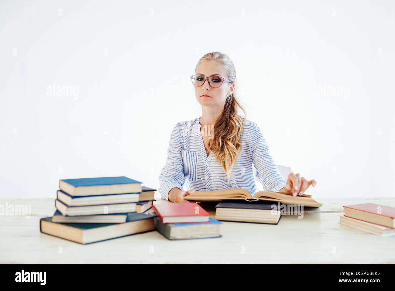 female teacher sitting at a table of many books Office Stock Photo - Alamy