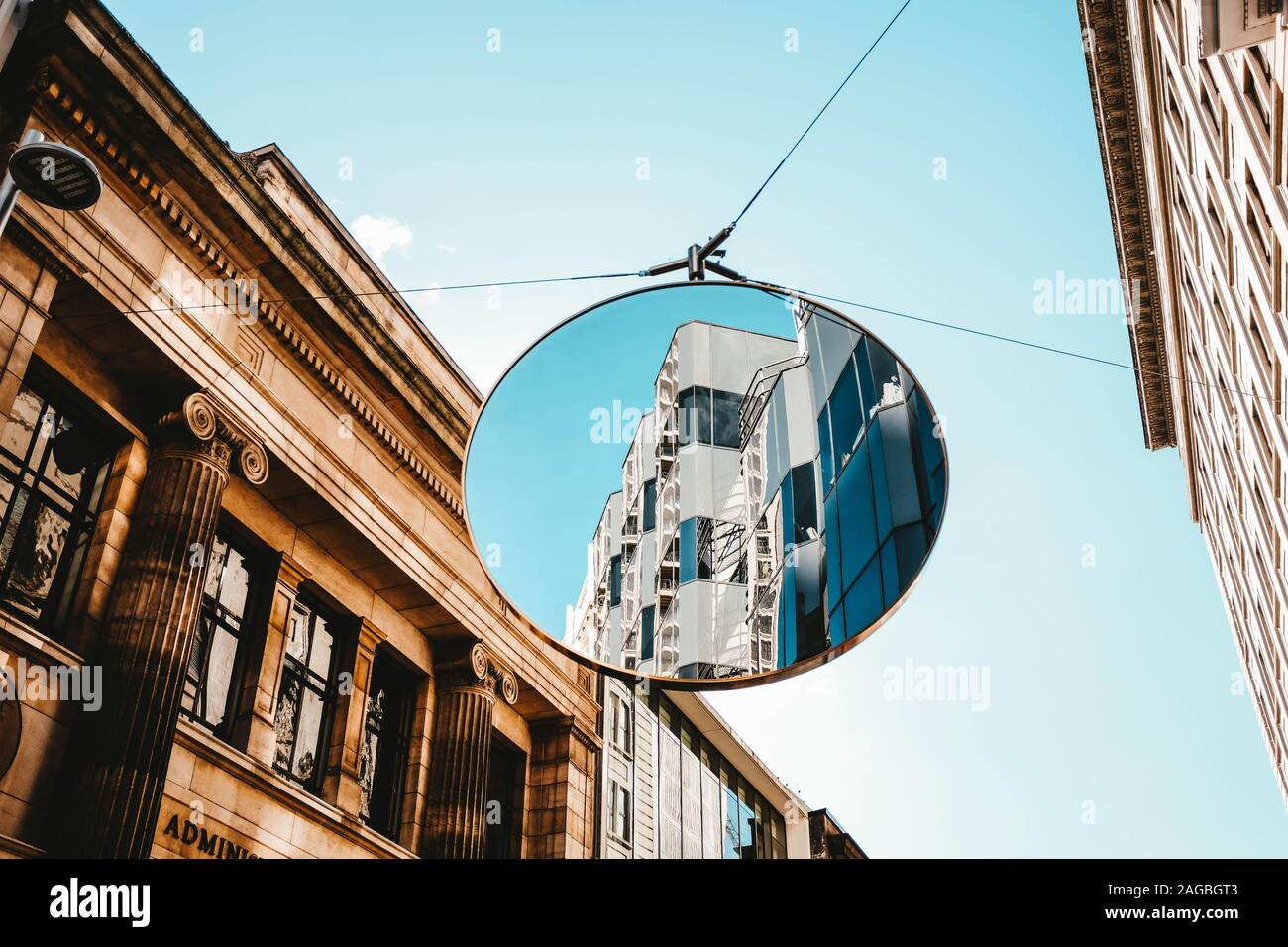 Beautiful modern building visible in a round mirror among old stone ...