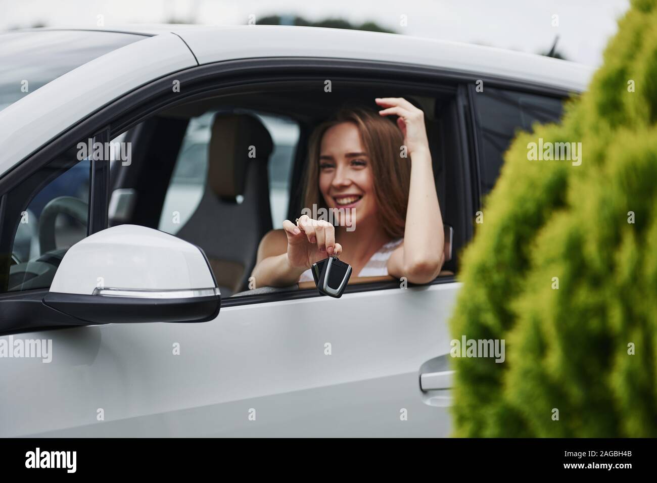 Feeling happy. Female driver showing her keys while sits inside of ...