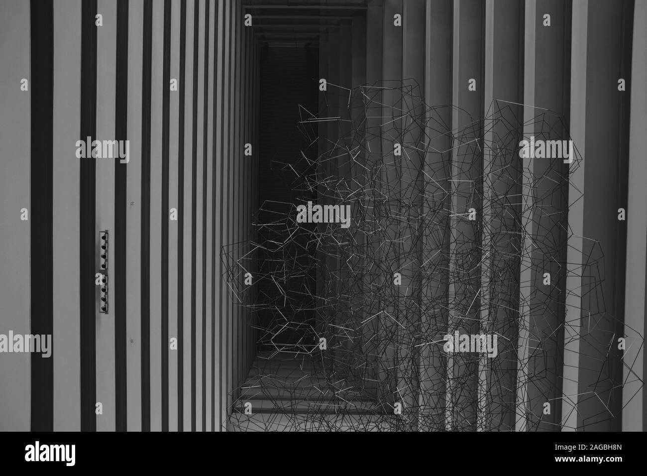 Grey scale shot of a metal structure in front of a striped wall Stock ...