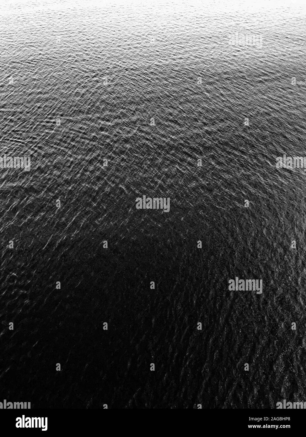 Vertical grey scale shot of the waves on the ocean captured from a high ...