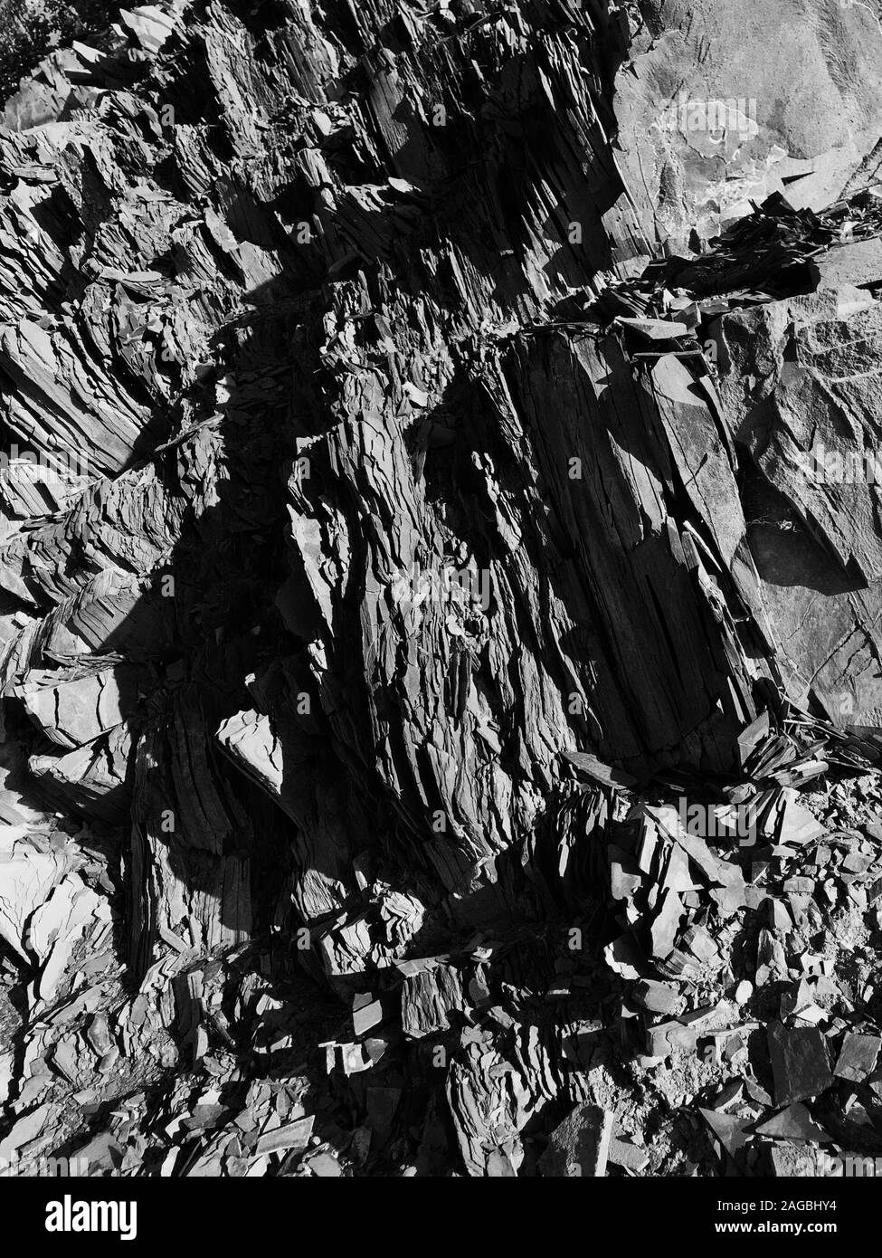 Vertical grey scale shot of the layers of old beautiful rocks on a ...