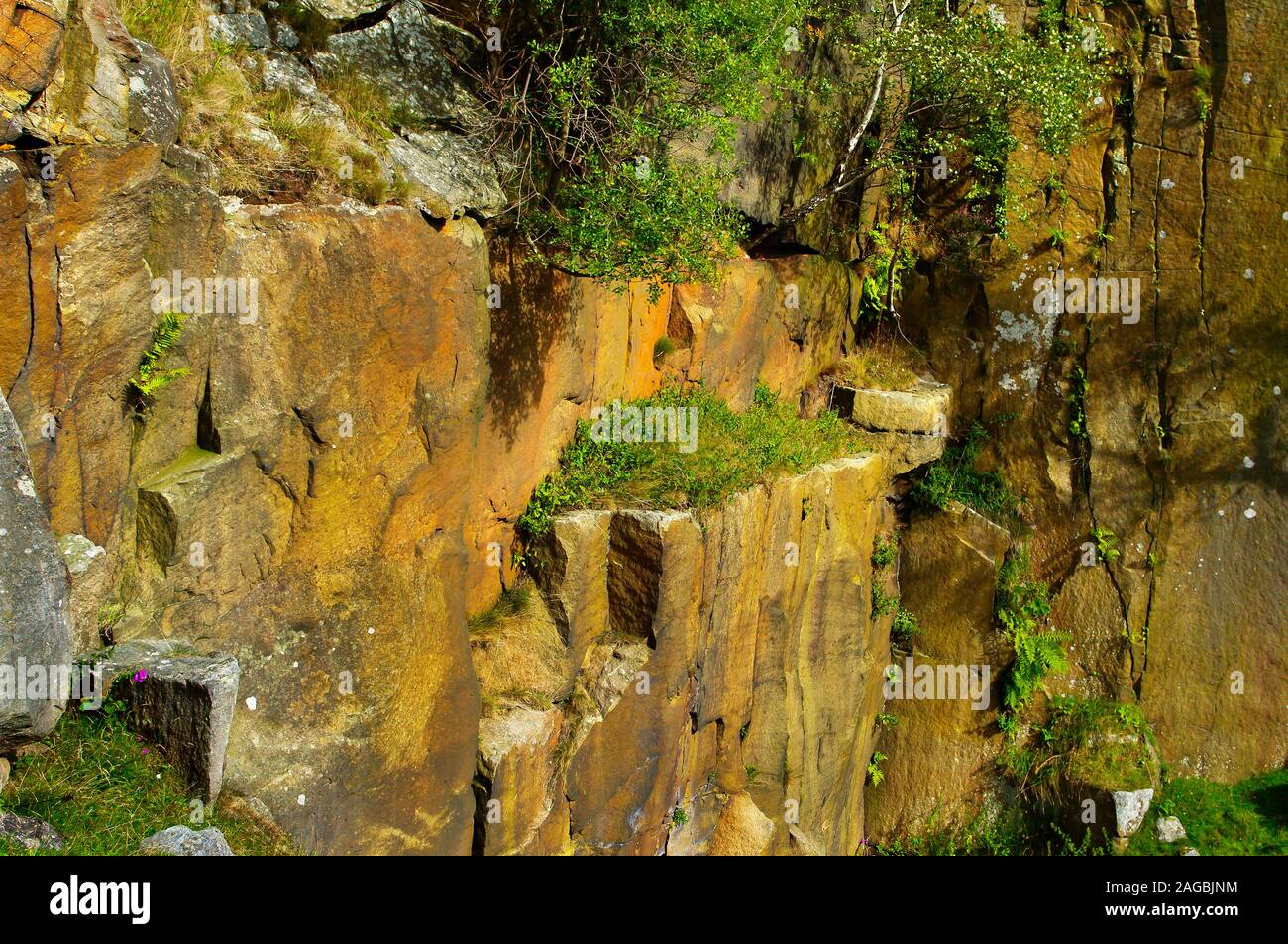 Abandoned worked gritstone faces in sunlight at Bole Hill Quarry near ...